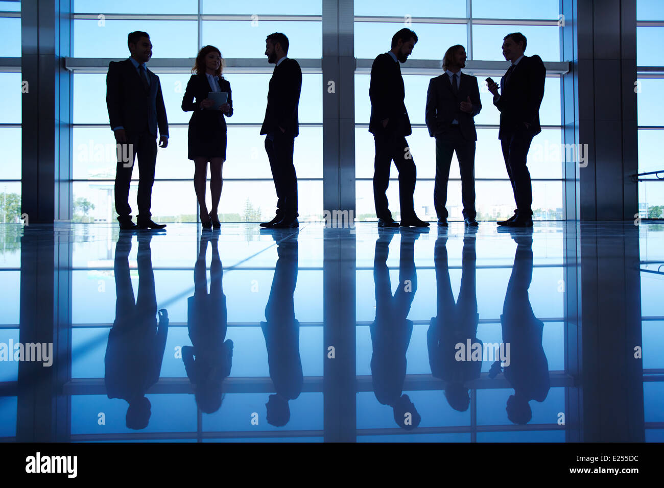Silhouettes of several office workers standing by the window and ...