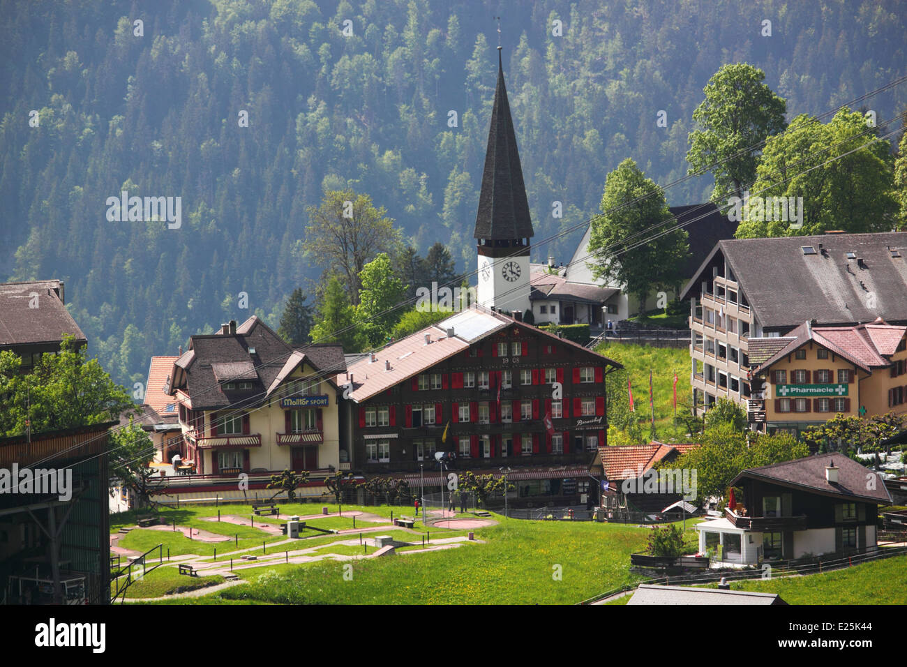 An alpine village with chalets and a church with a spire overlooking a ...