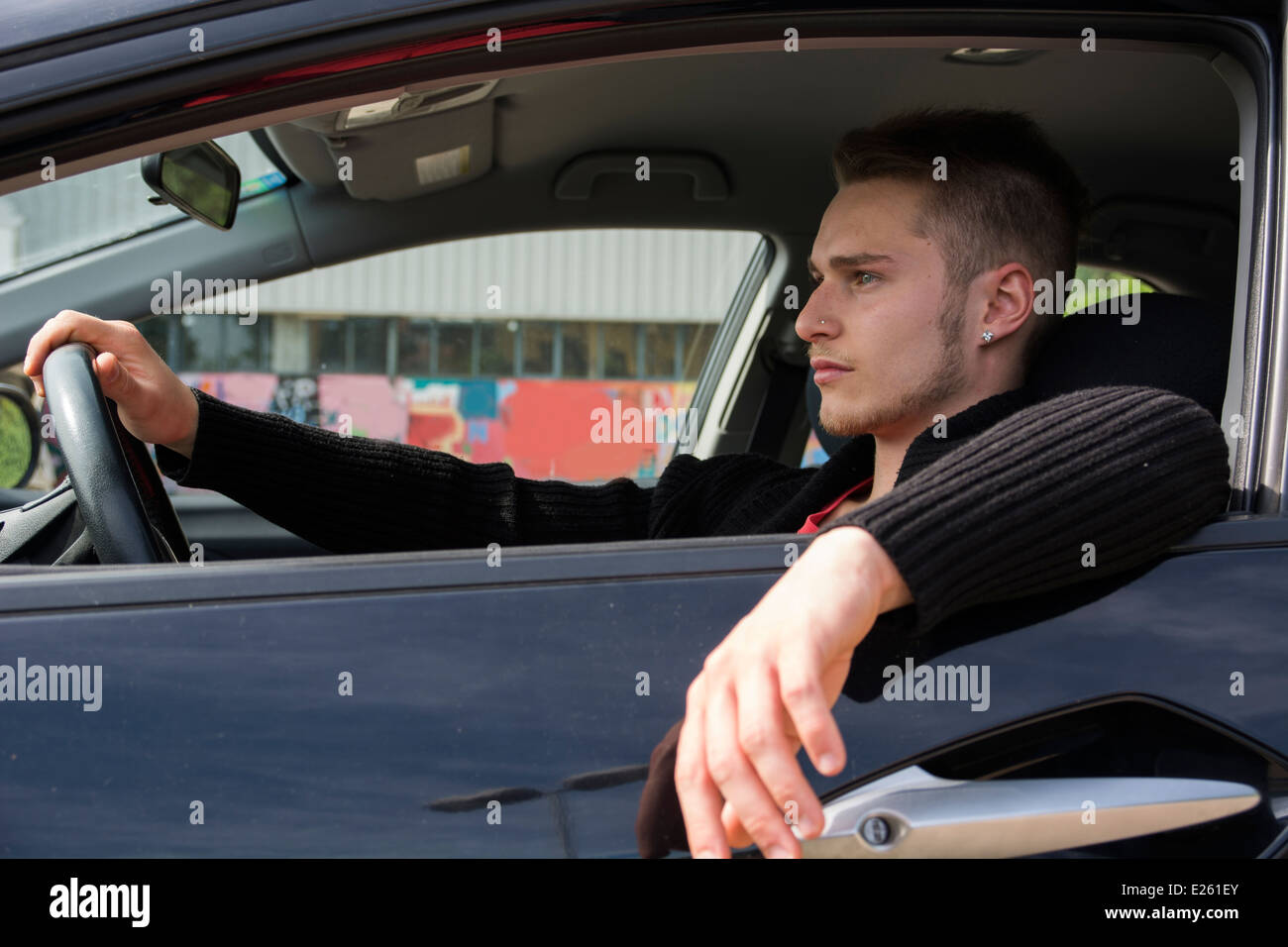 Handsome blond young man sitting in his car, looking in front of him ...