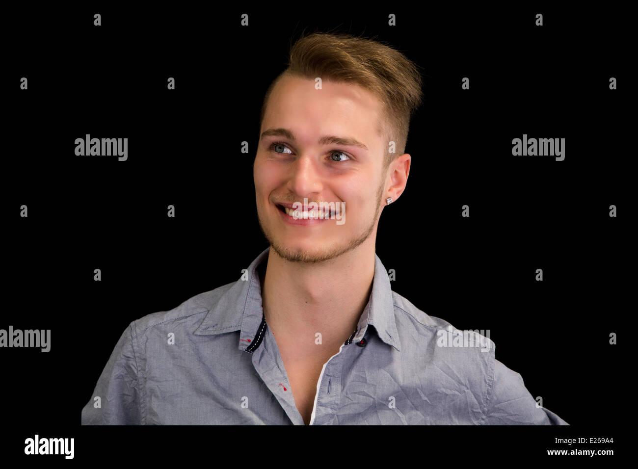 Attractive blond, blue eyed young man smiling and looking away ...