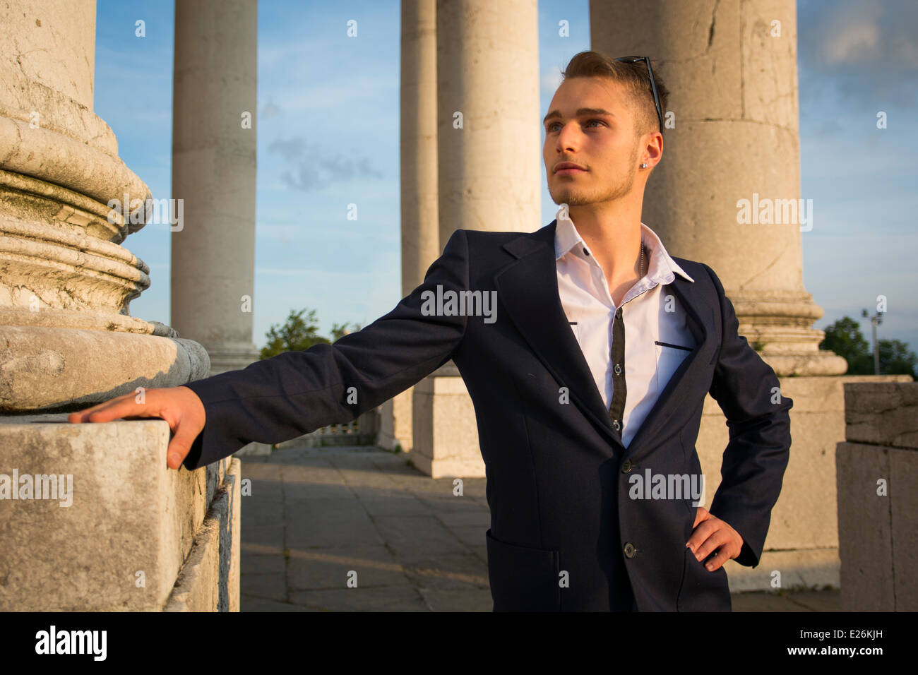 Handsome blond young man among marble columns at sunset Stock Photo - Alamy