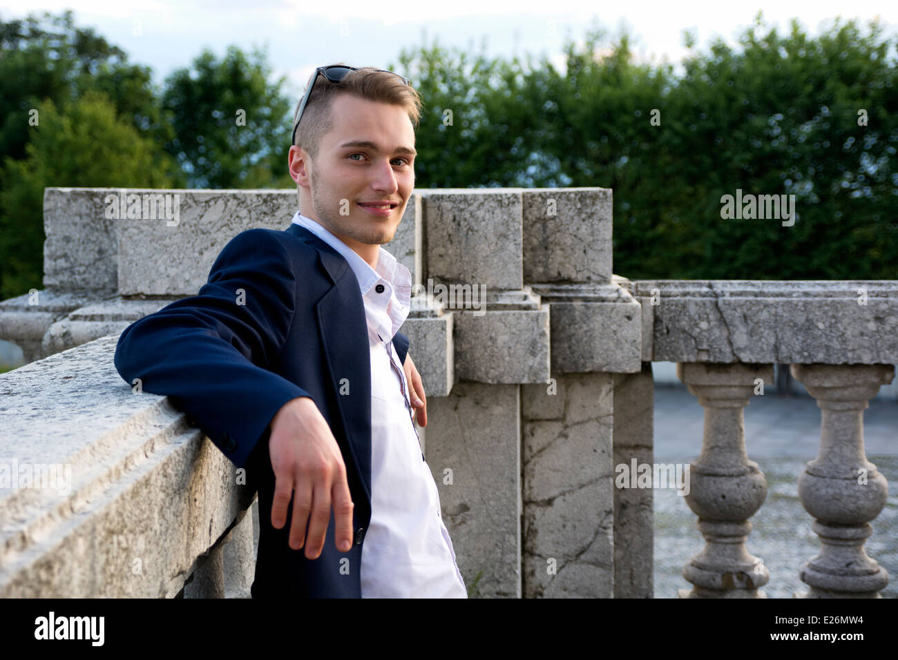 Handsome blond young man on marble banister smiling at camera Stock ...