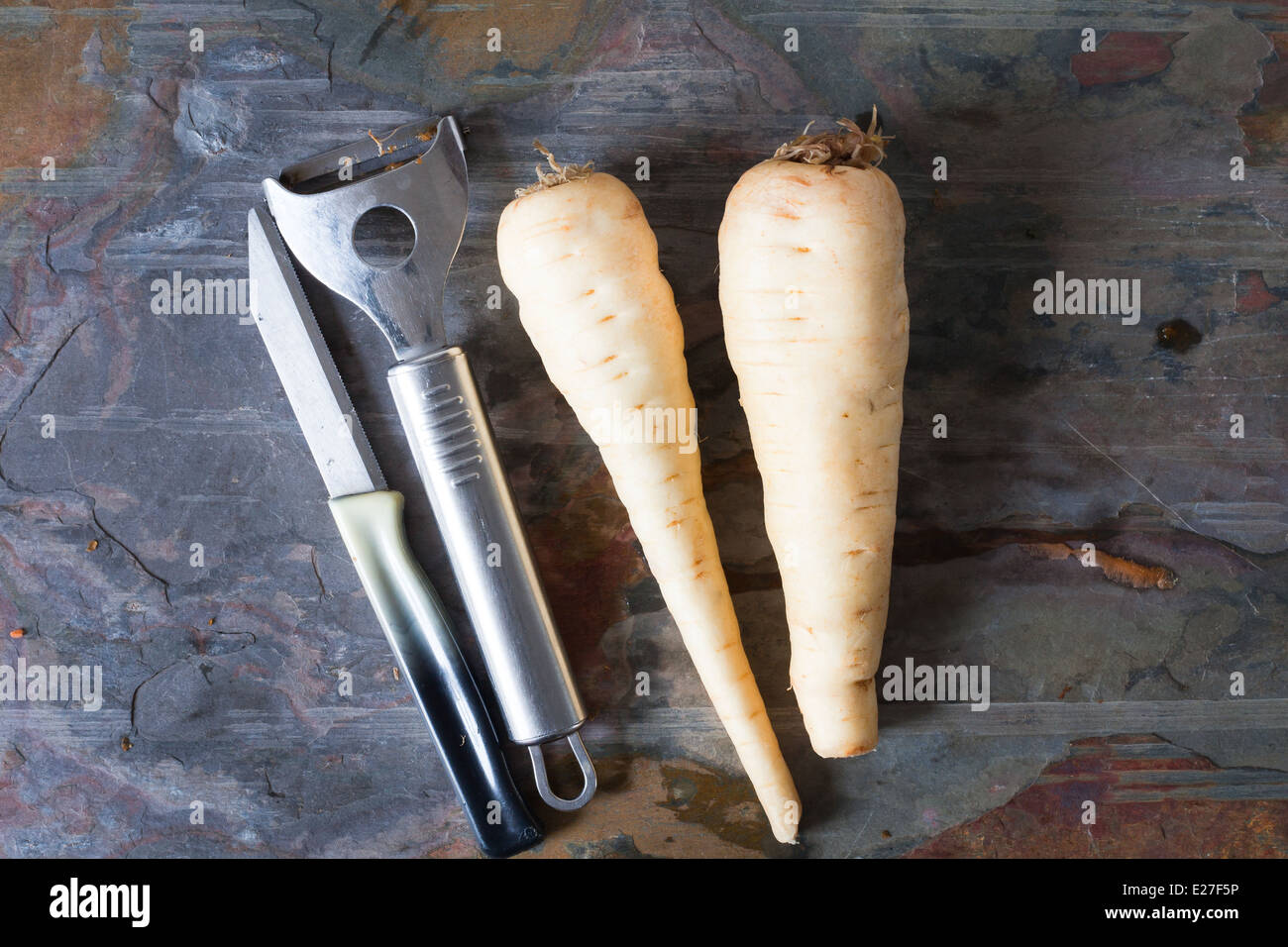 Raw parsnips on a worktop with a peeler and knife Stock Photo - Alamy
