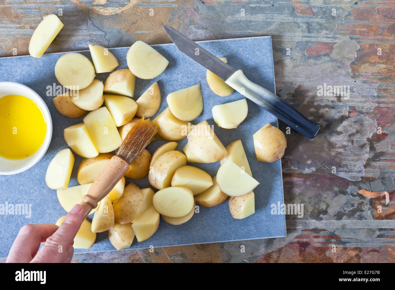 Raw chopped potatoes being brushed with oil for roasting Stock Photo ...