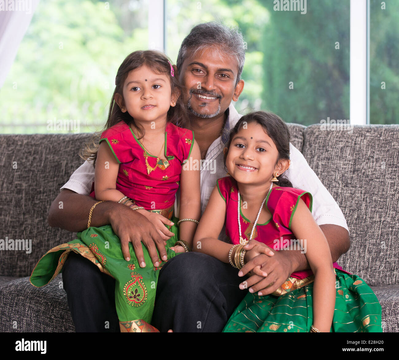 indian father with his daughter smiling and lookin at camera on living ...