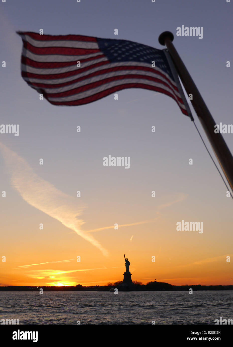 The American flag flying over the Statue of Liberty in the distance at ...