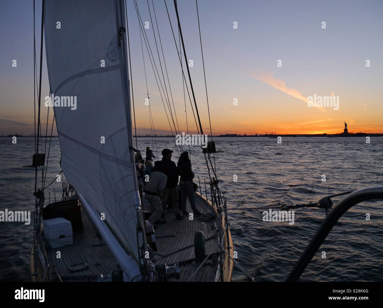 People on a sailing boat watching the sunset behind the Statue of ...