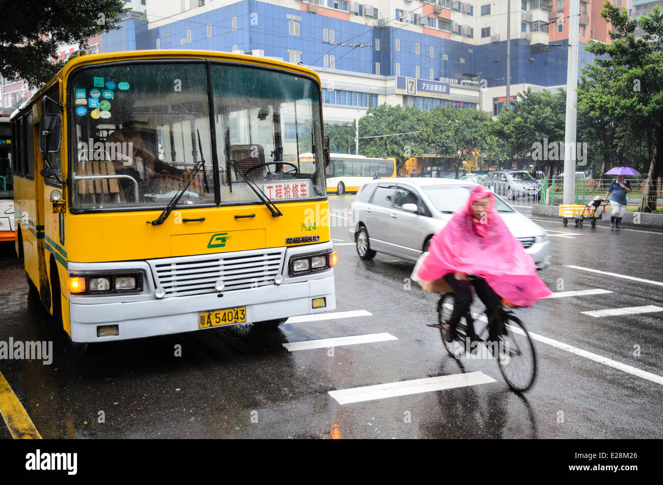 A cyclist in a waterproof cape passes on old bus on a rainy day ...