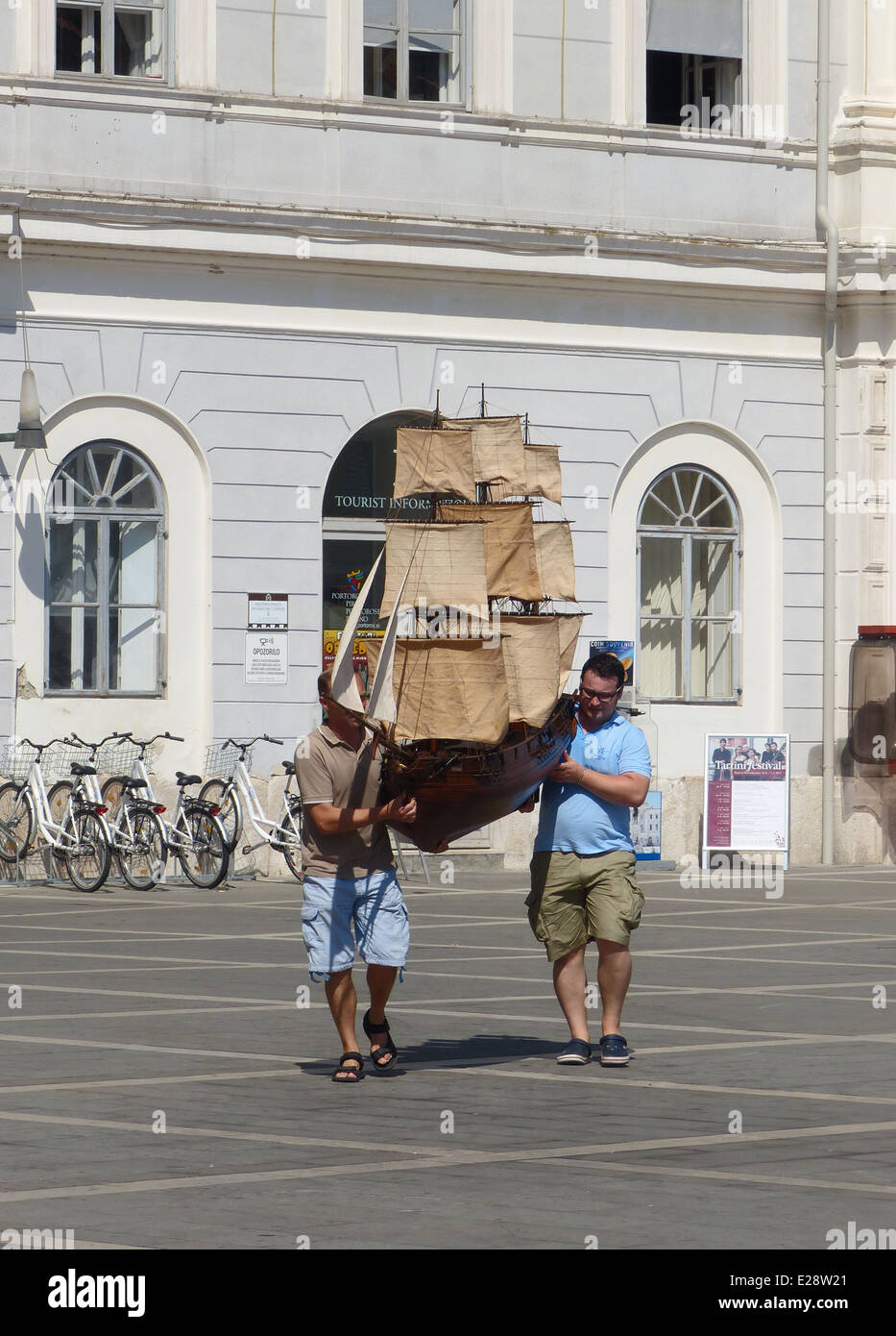 Two men carrying a large model ship across a town square Stock Photo ...
