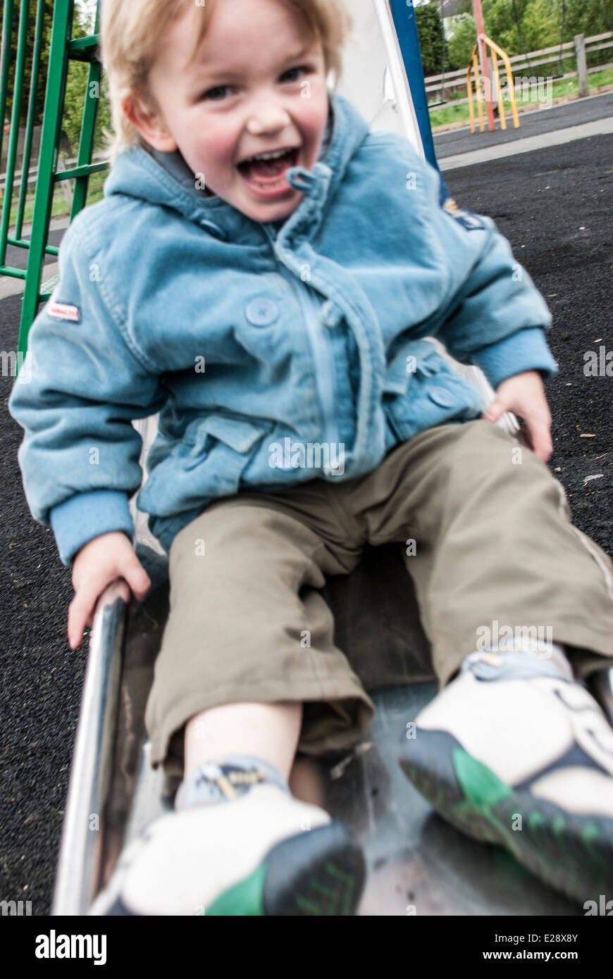Young boy enjoying play on slide Stock Photo - Alamy