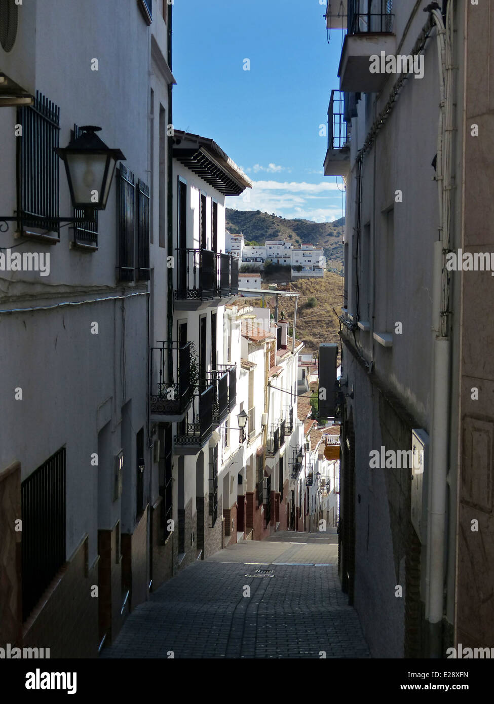 A long narrow street in Alora, Spain with hill views in the distance ...