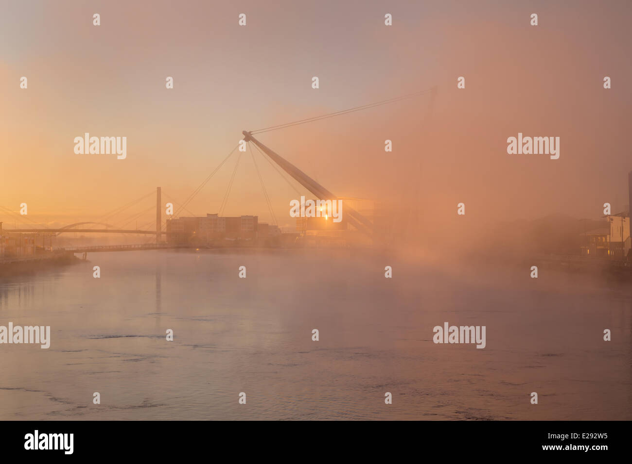 View of tidal river with footbridge and university building shrouded in ...