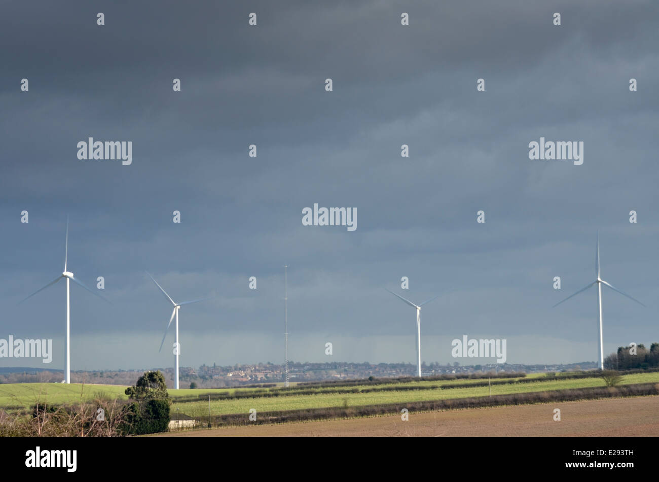 four wind turbines against dark grey clouds Stock Photo - Alamy