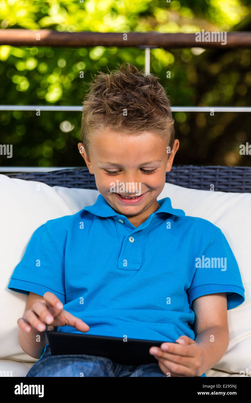 Caucasian boy sitting with his tablet outside during summer time Stock ...