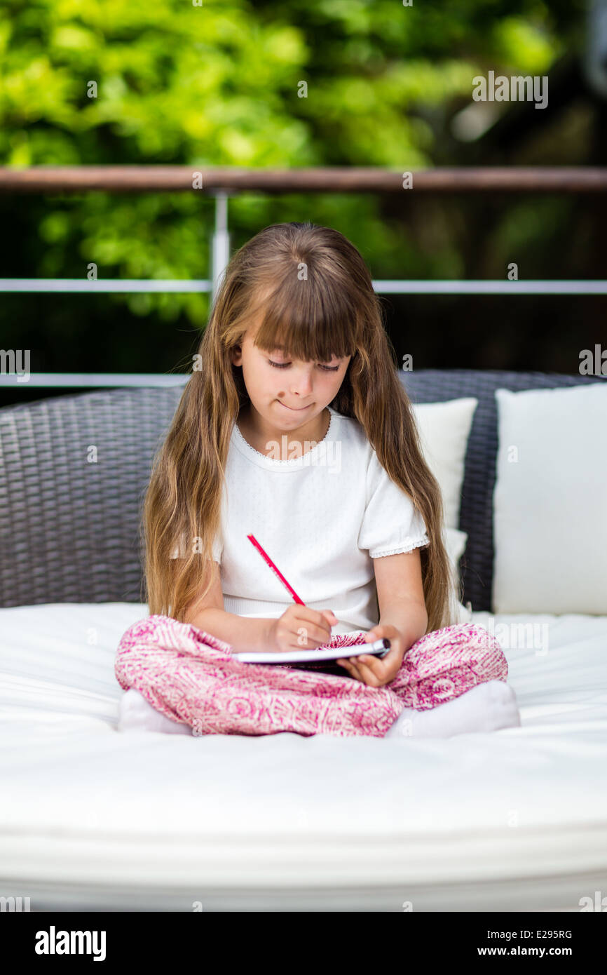 Young caucasian girl sitting on patio and writing on her notepad Stock ...