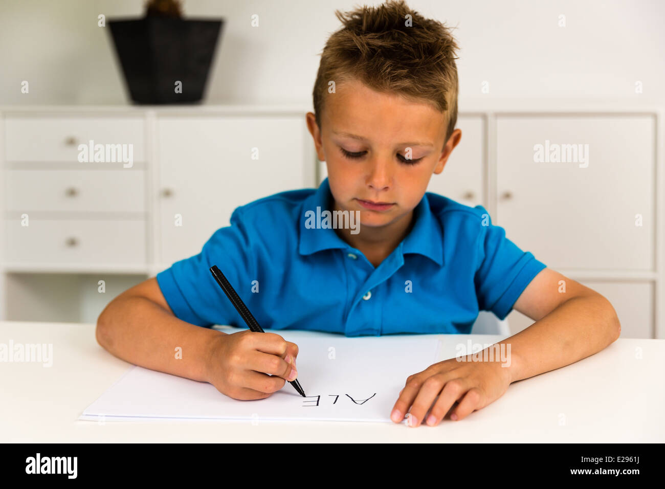 Young caucasian boy writing letters on a white piece of paper Stock ...