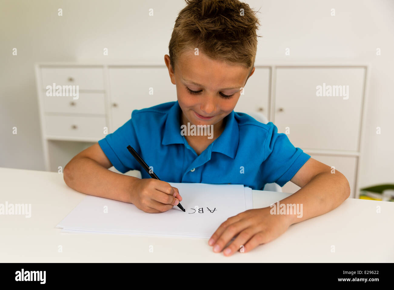 Young caucasian boy writing letters on a white piece of paper Stock ...