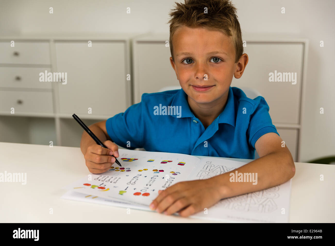 Young caucasian boy doing his elementary school homework while sitting ...