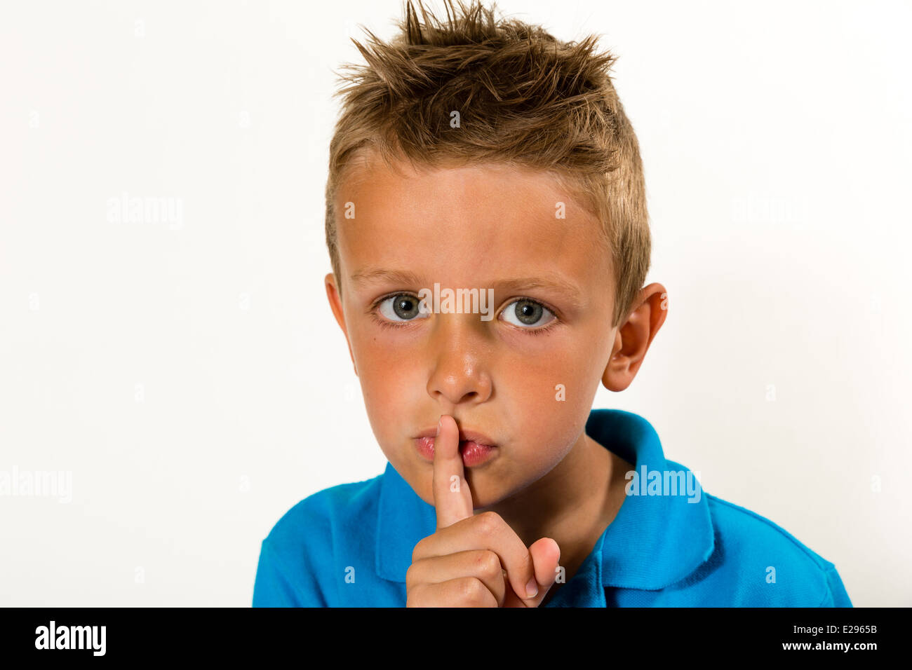 Caucasian boy doing a Please Keep Quiet gesture towards the camera ...
