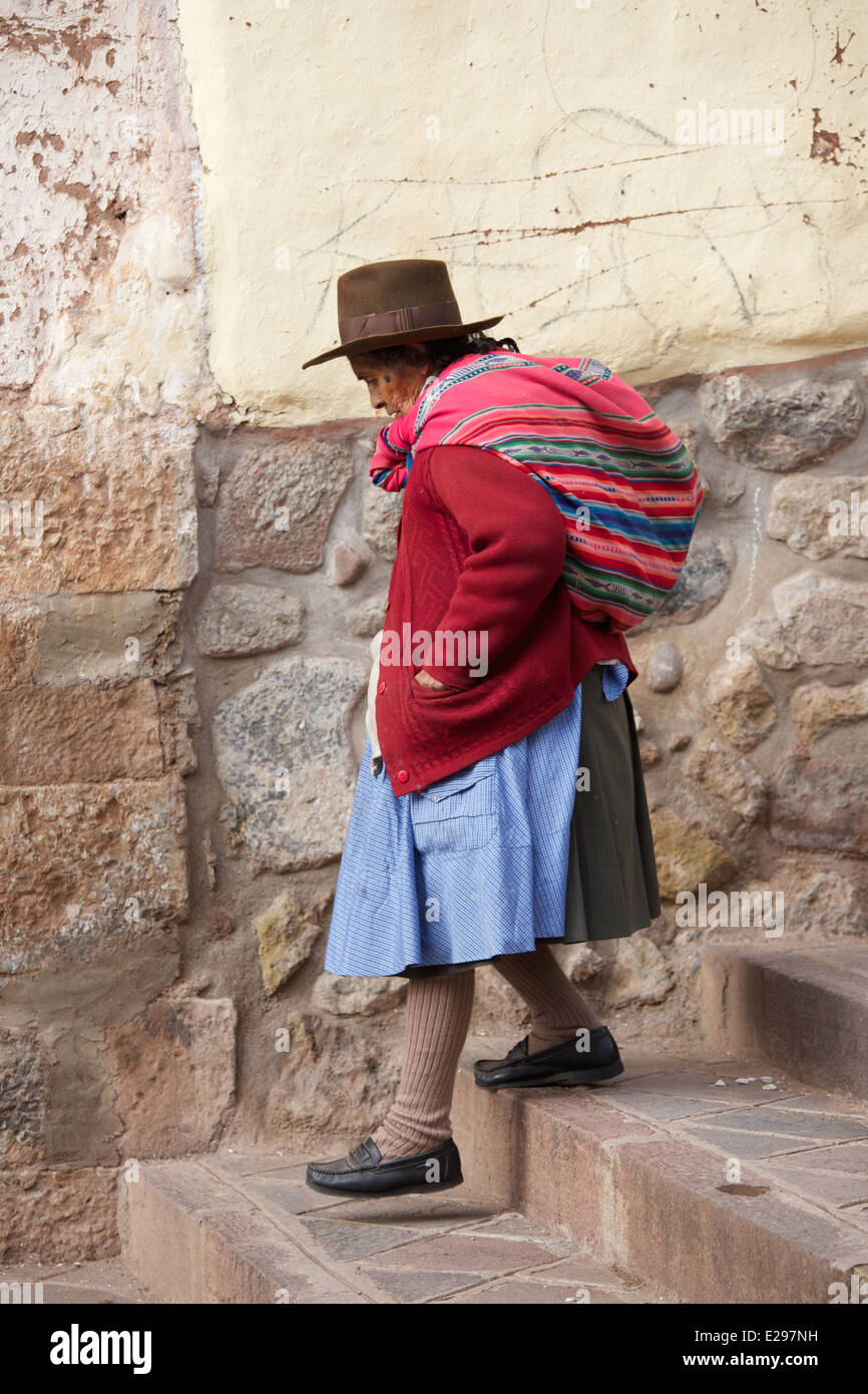 An old woman in traditional dress walks down the street in Cusco, Peru ...