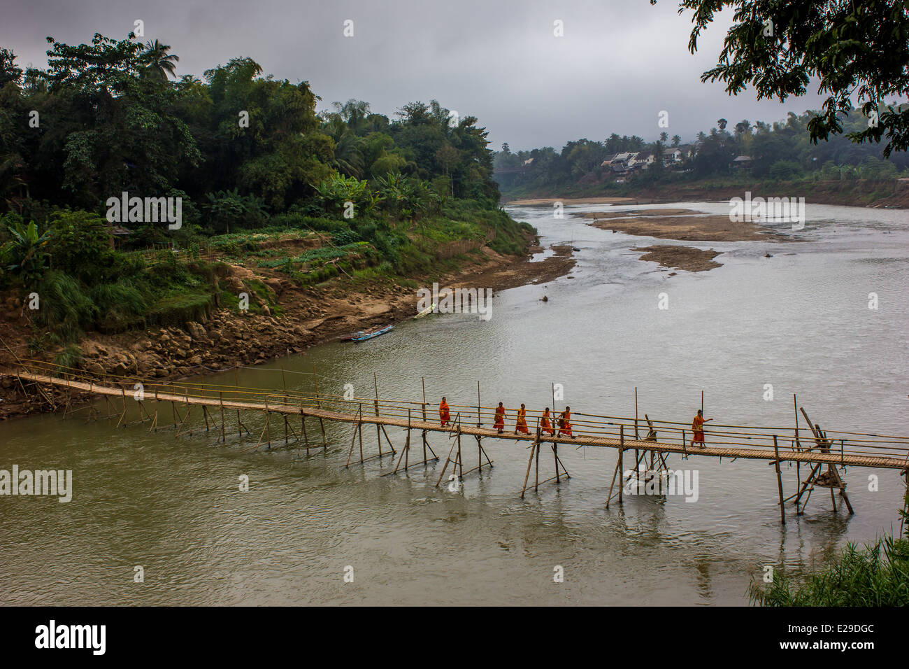Buddhist monks cross a bridge over the Mekong river in Luang Prabang ...