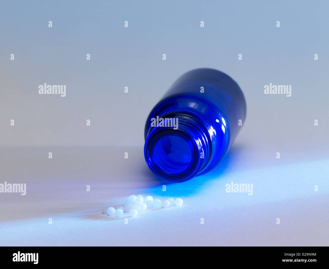 a open small blue bottle with some globules around Stock Photo - Alamy