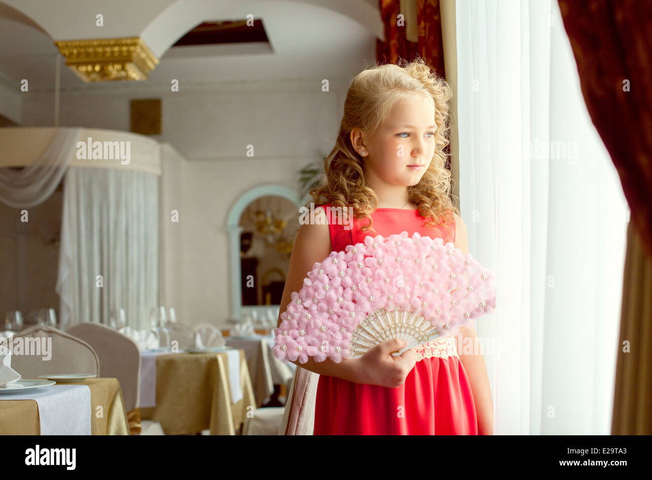 Elegant girl posing with fan standing at window Stock Photo - Alamy