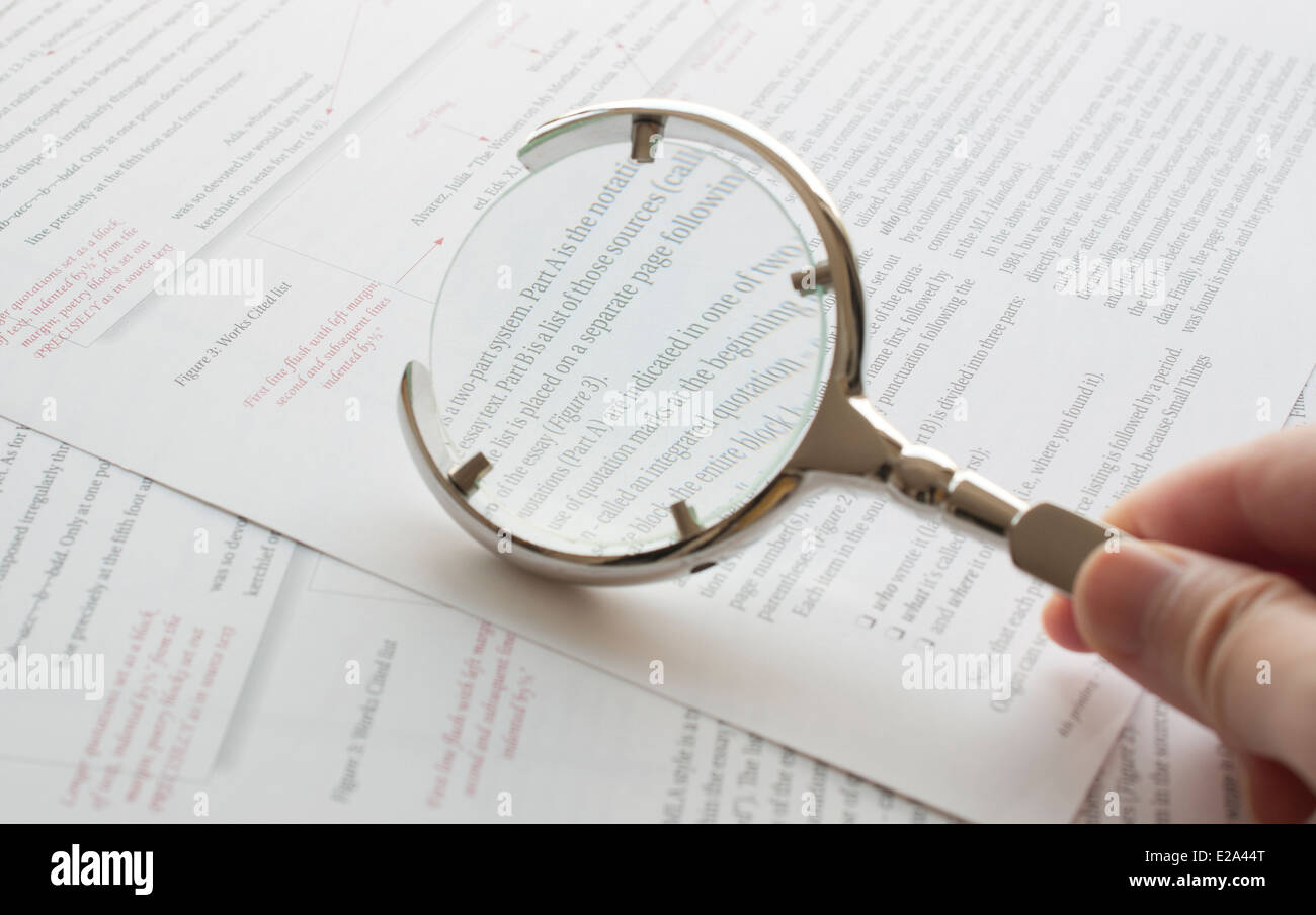 Close up hand holding magnifying glass to read document Stock Photo - Alamy
