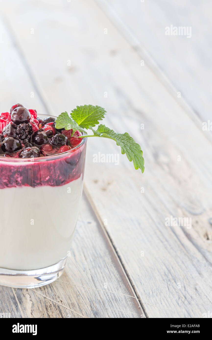 Yoghurt with red Berries in a glass on a wooden table Stock Photo - Alamy