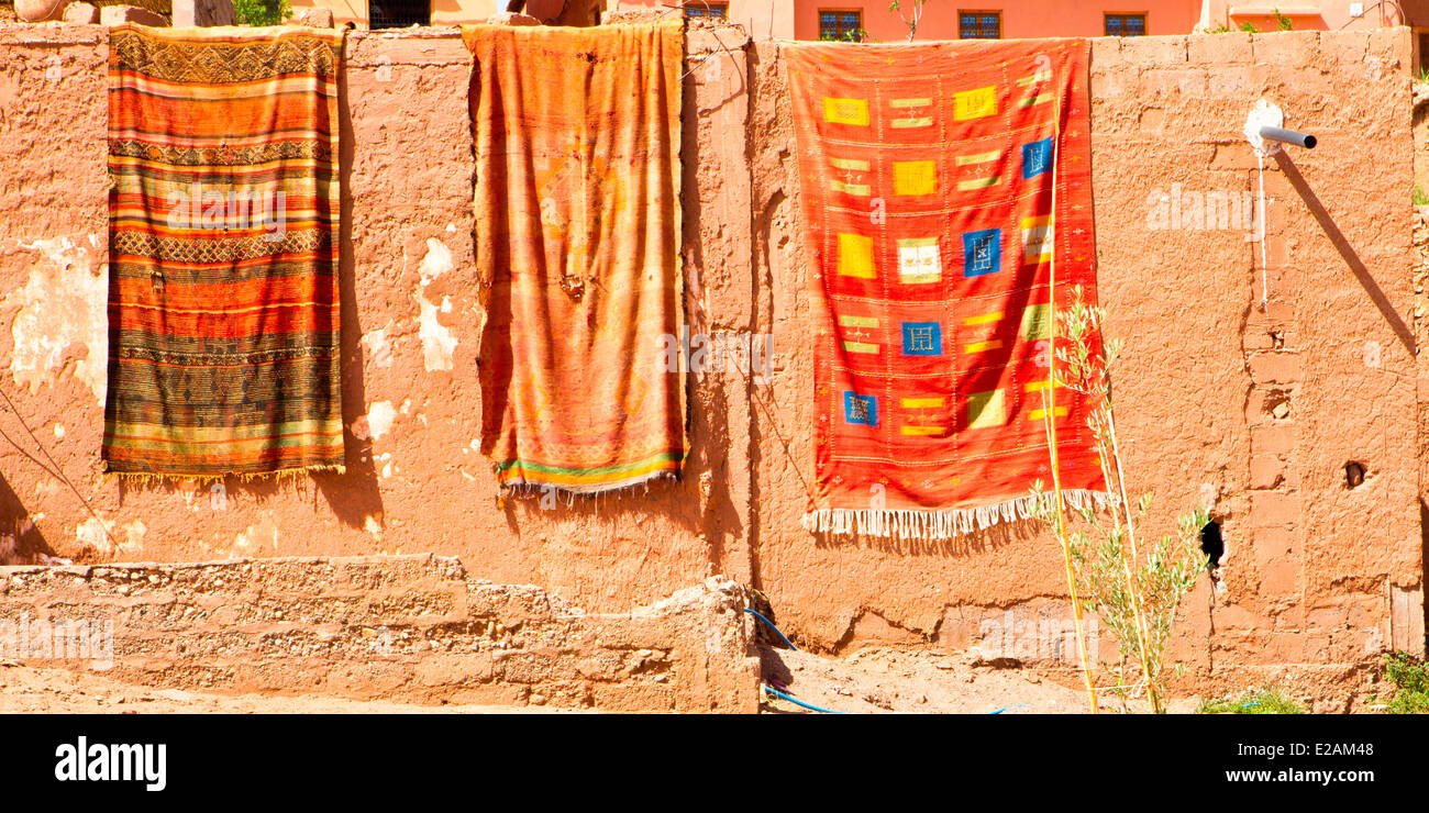 Colourful carpets hang over traditional ochre pise walls at Ait ...