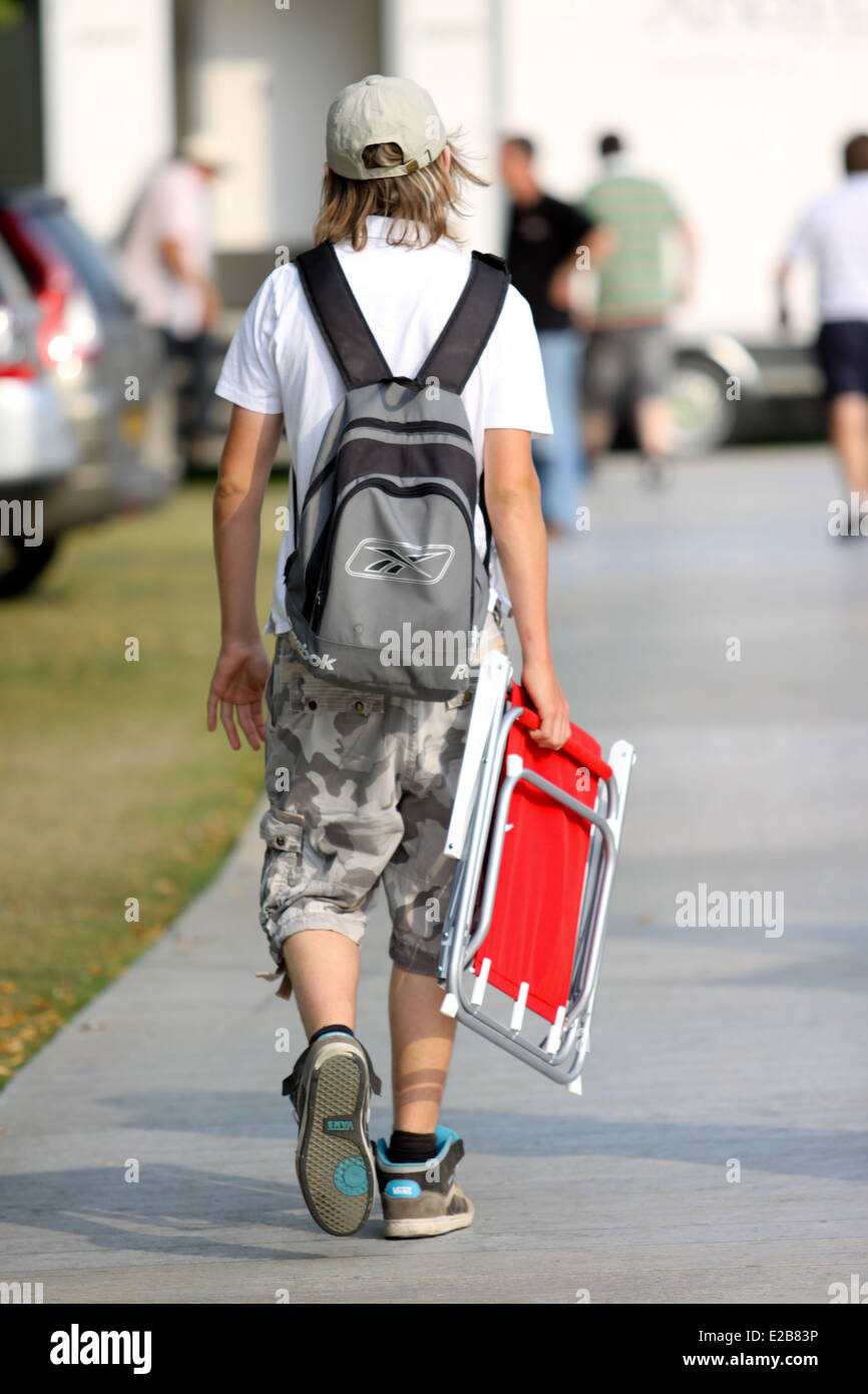Young man carrying deck chair at a festival Stock Photo - Alamy