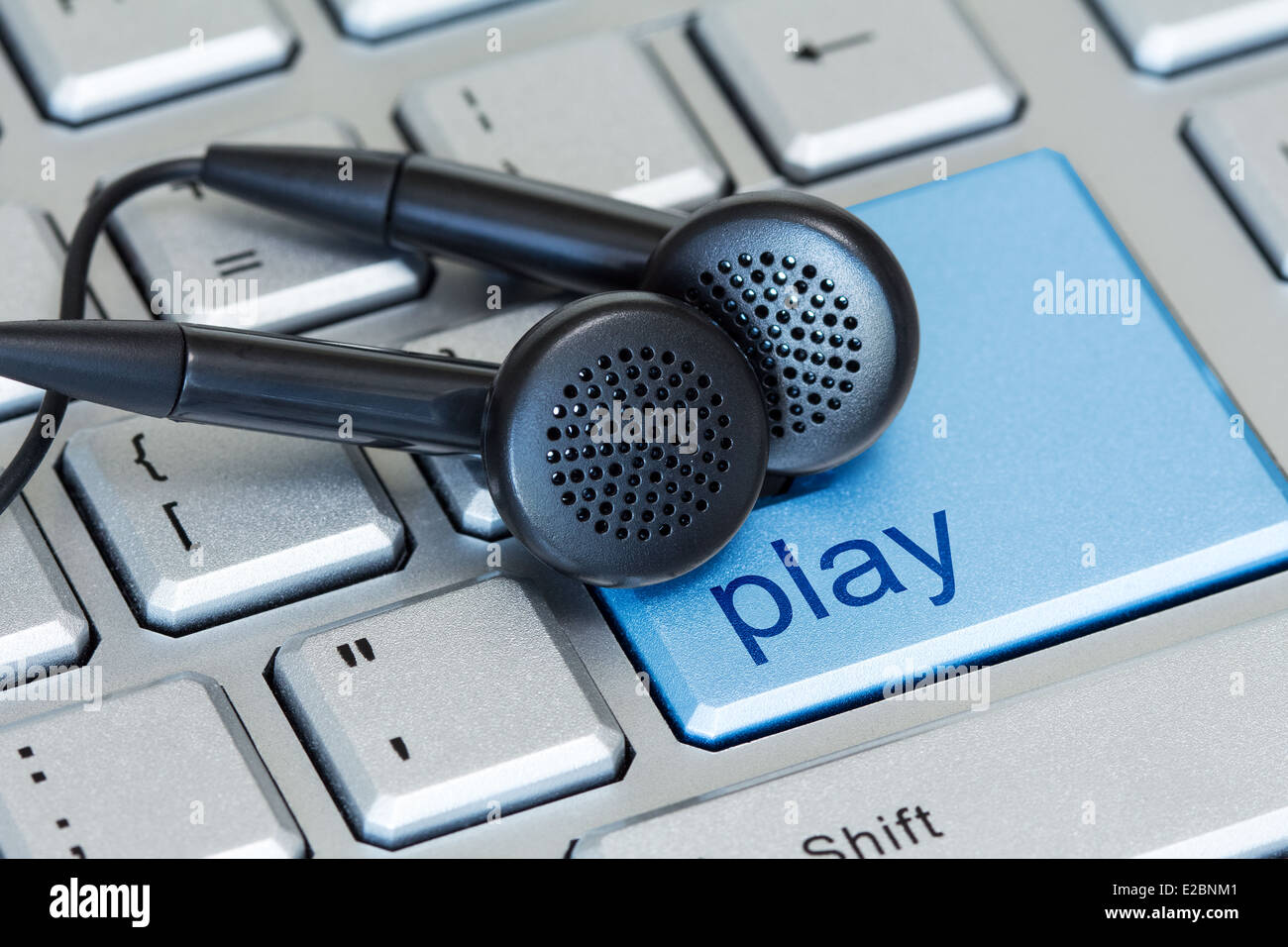 Earphones on computer keyboard with a play button Stock Photo - Alamy