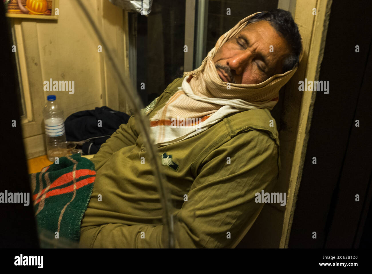 An Indian night time security guard, or chawkidar, sleeps in his wooden ...