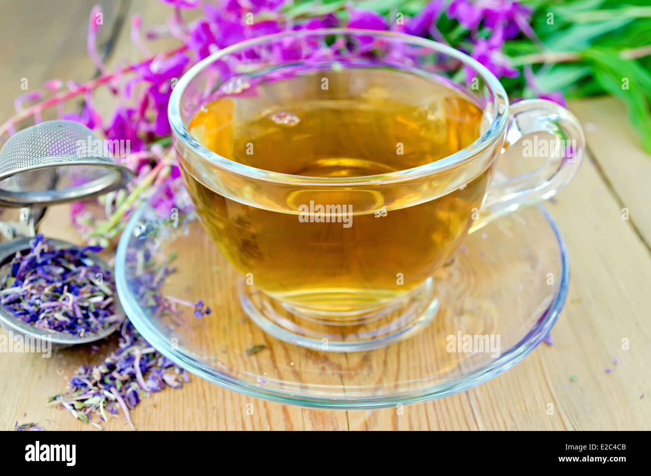 Herbal tea in a glass cup, metal sieve with dry flowers fireweed ...