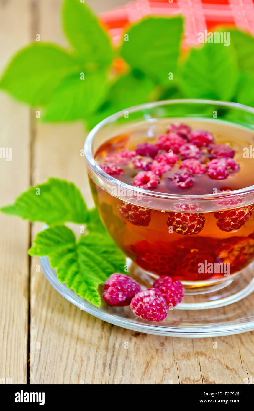 Tea with raspberries in a glass cup, green leaves raspberry, napkin on ...