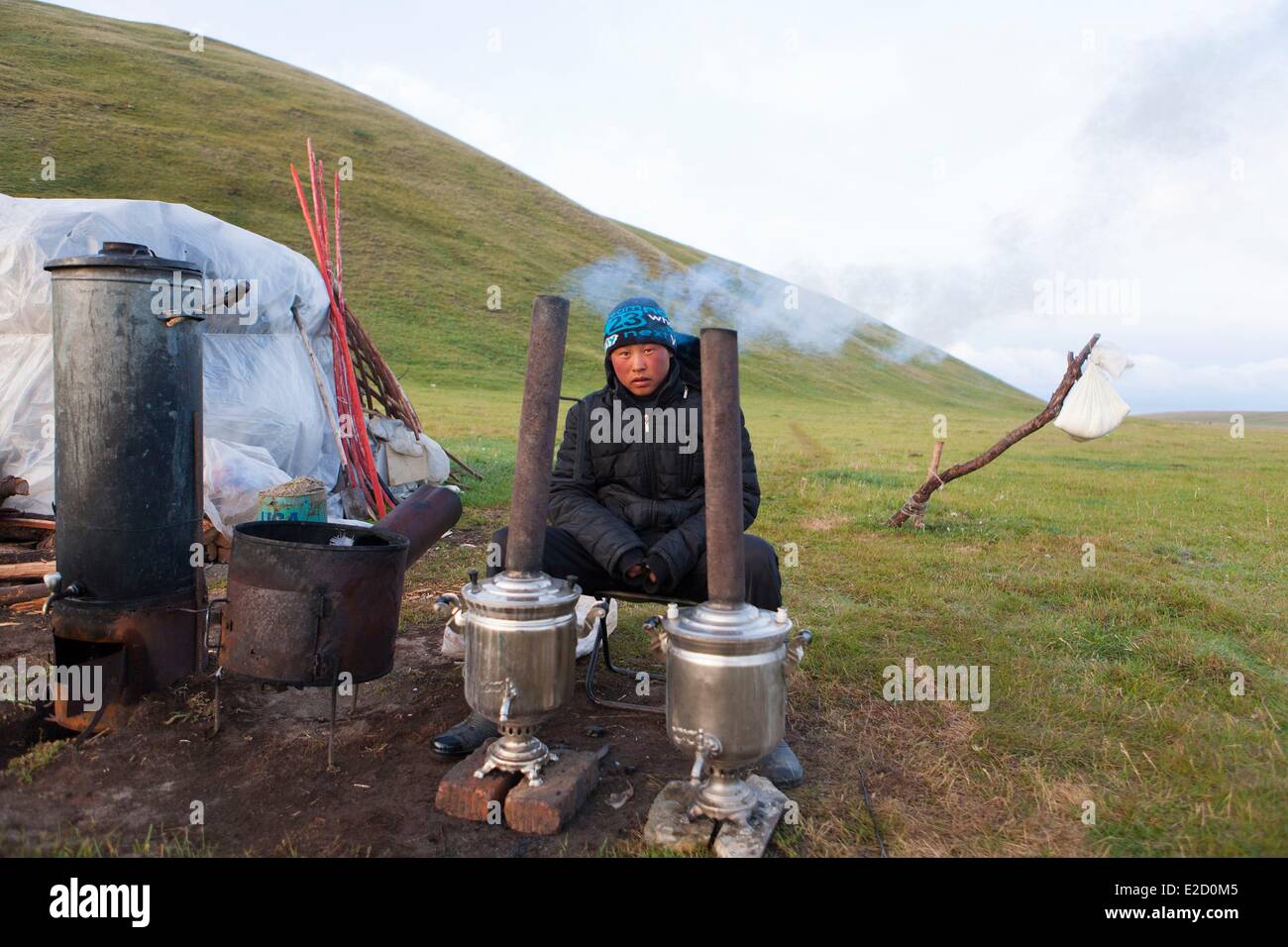 Kyrgyzstan Naryn Province teen boy seated by the samovars at a yurt ...
