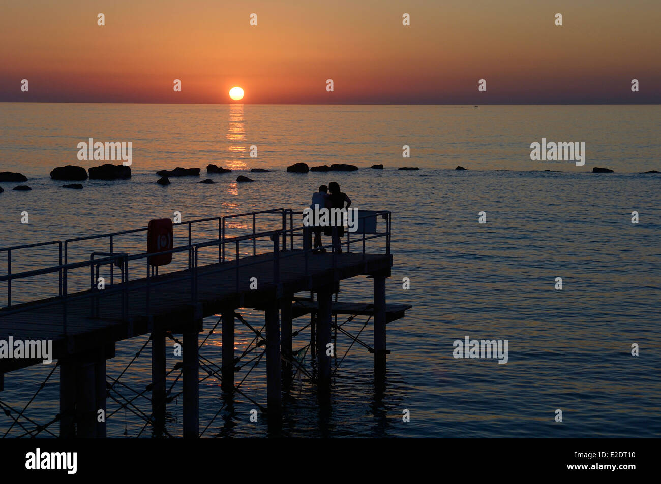 A silhouetted couple watch the sun setting out at sea, Cyprus Stock ...