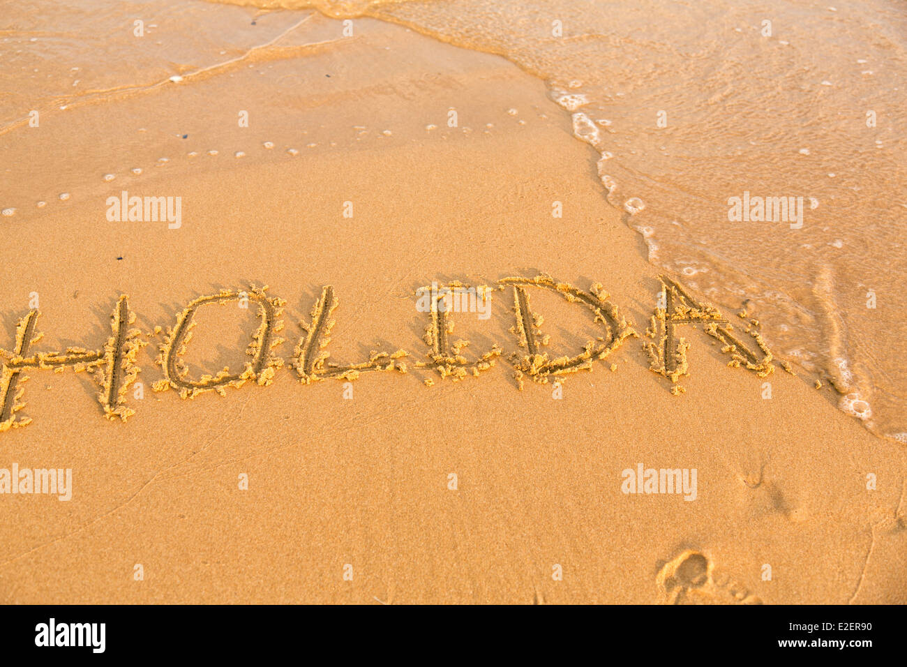 Word holiday on the yellow sandy beach, text Stock Photo - Alamy