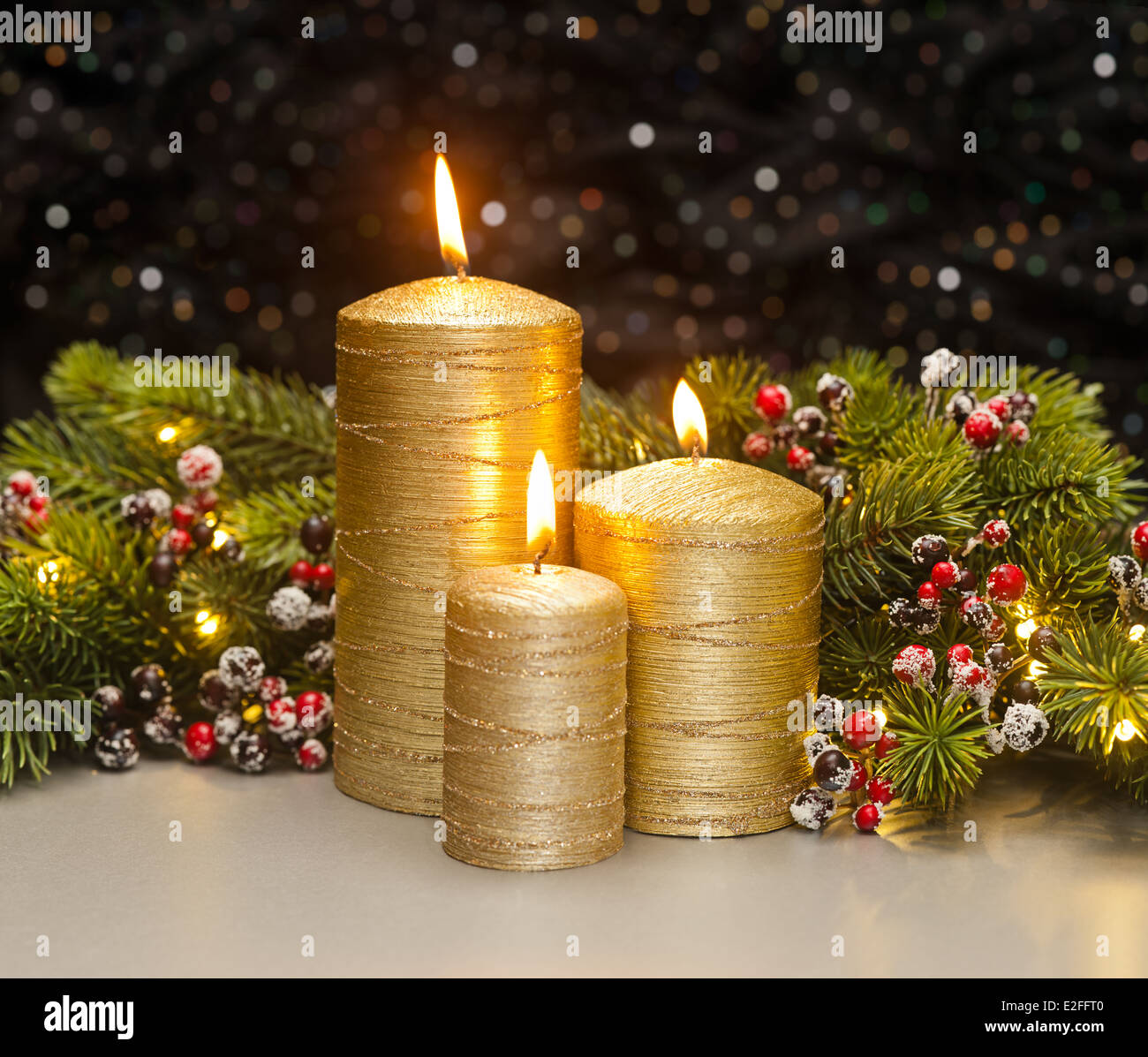 Three golden Candles with Christmas tree branches and red berries ...