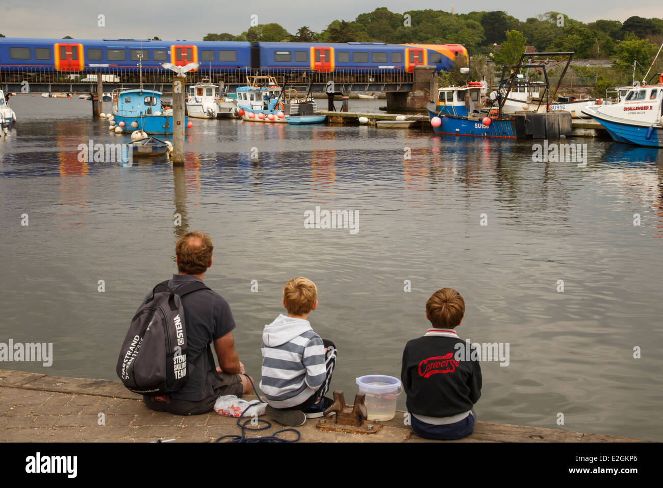 Family sat on Lymington quayside fishing - train and boats in ... Family sat on Lymington quayside fishing - train and boats in ...