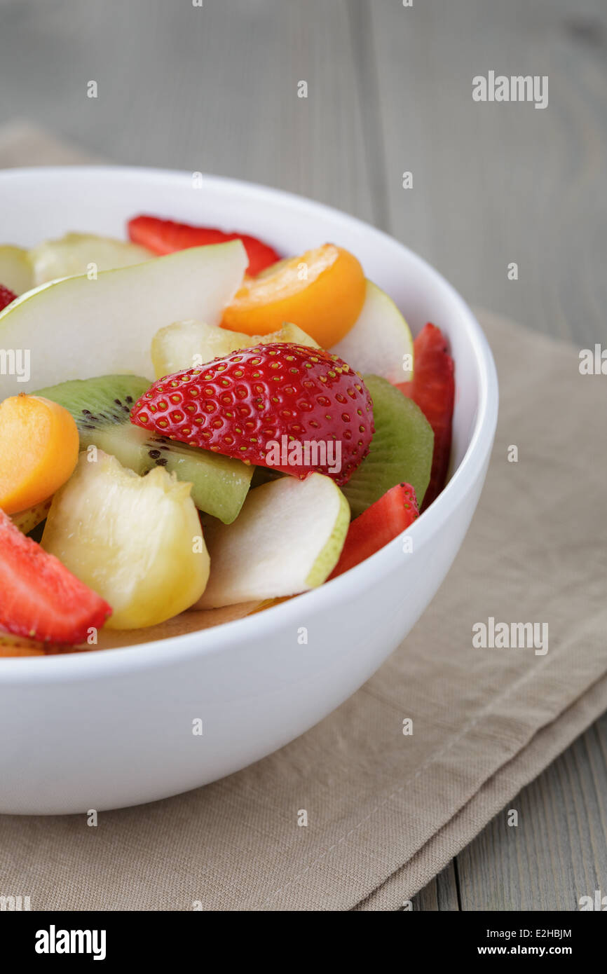 fresh mix fruit salad with strawberry, kiwi and peach, on wood table ...