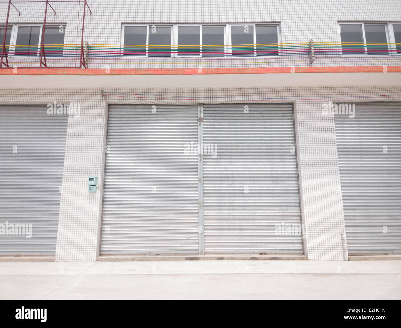 blank metal shutter doors on commercial shop front, symmetrical ...
