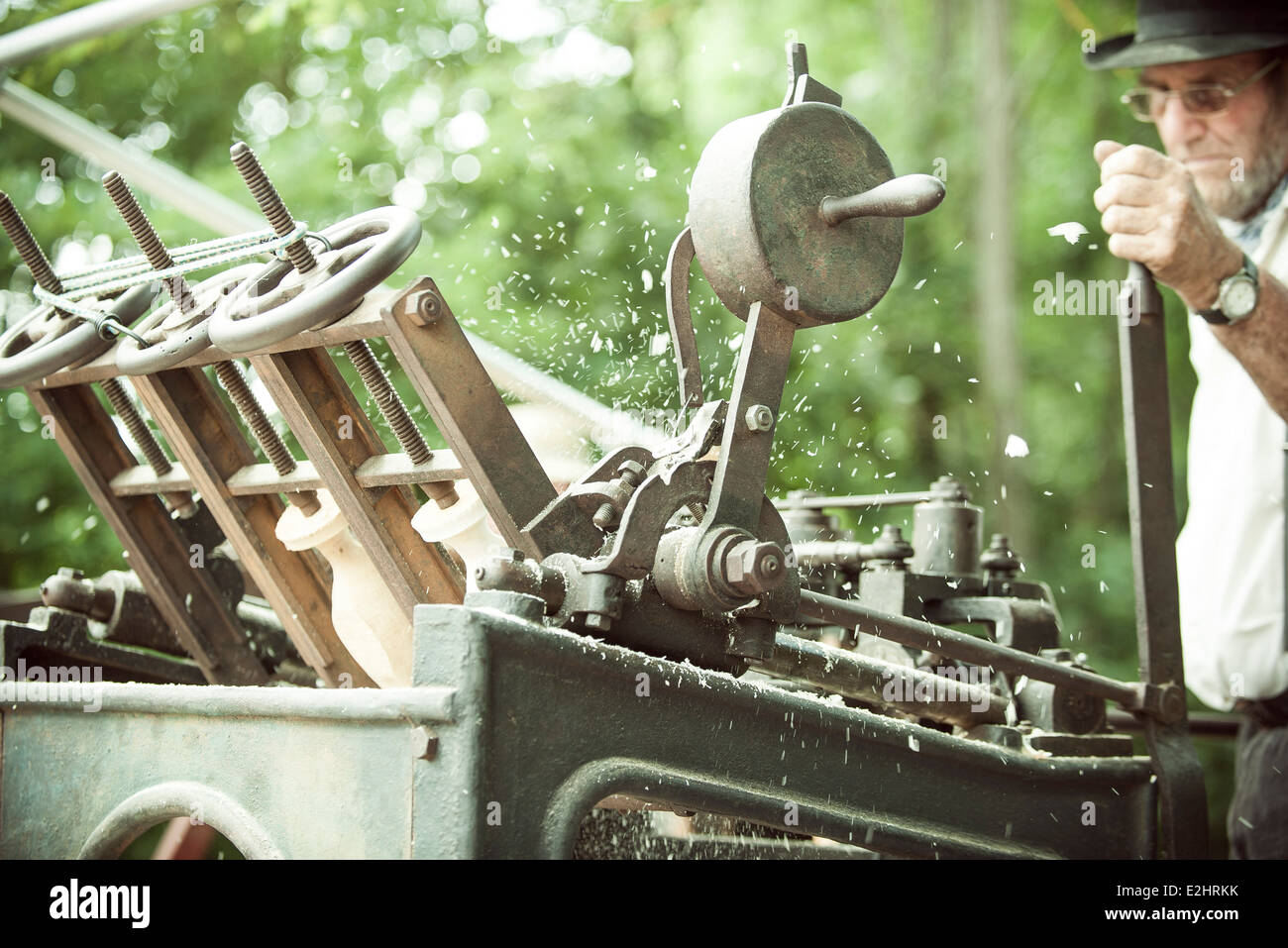 Man using wood lathe to fashion new spokes for horse-drawn wagon wheel ...