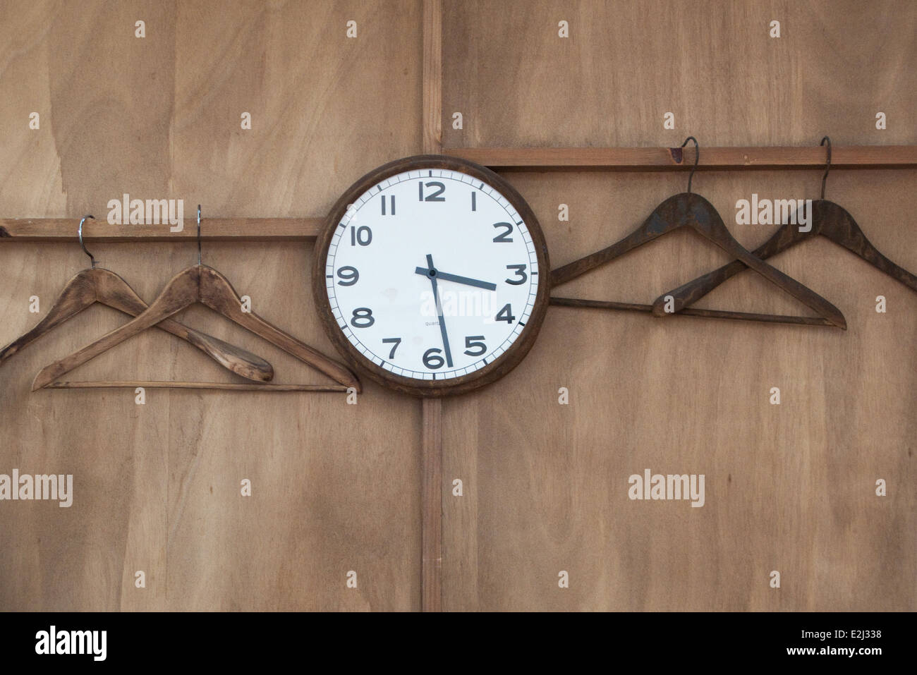 Wall clock and empty hangers on coat rack Stock Photo - Alamy