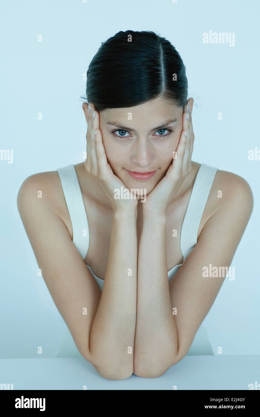 Young woman leaning on elbows holding head, portrait Stock Photo - Alamy