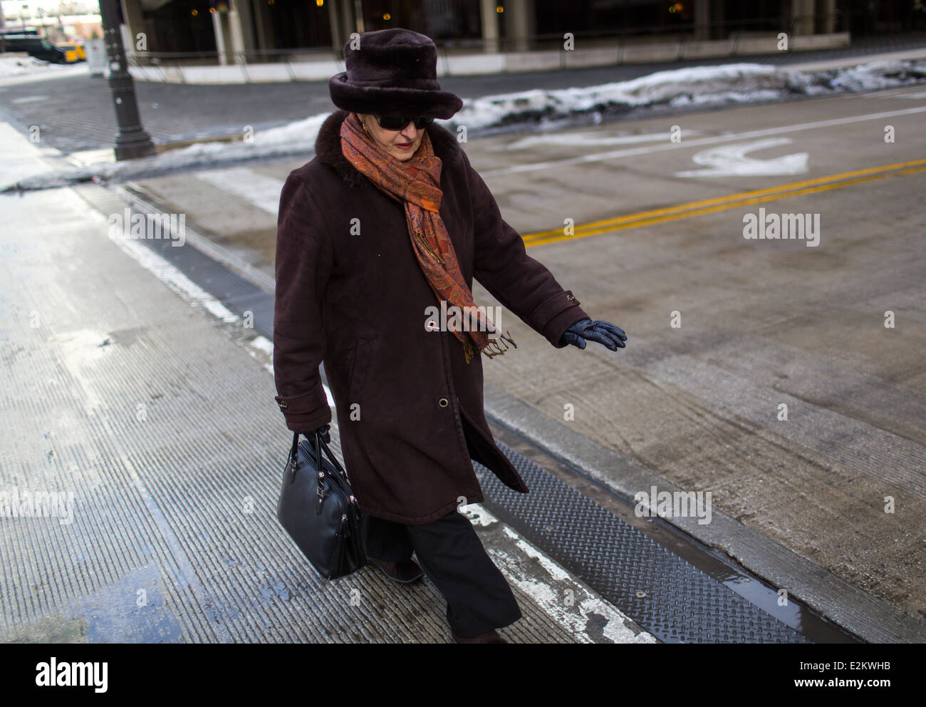 A woman carefully crosses an icy street in downtown Chicago, Illinois ...