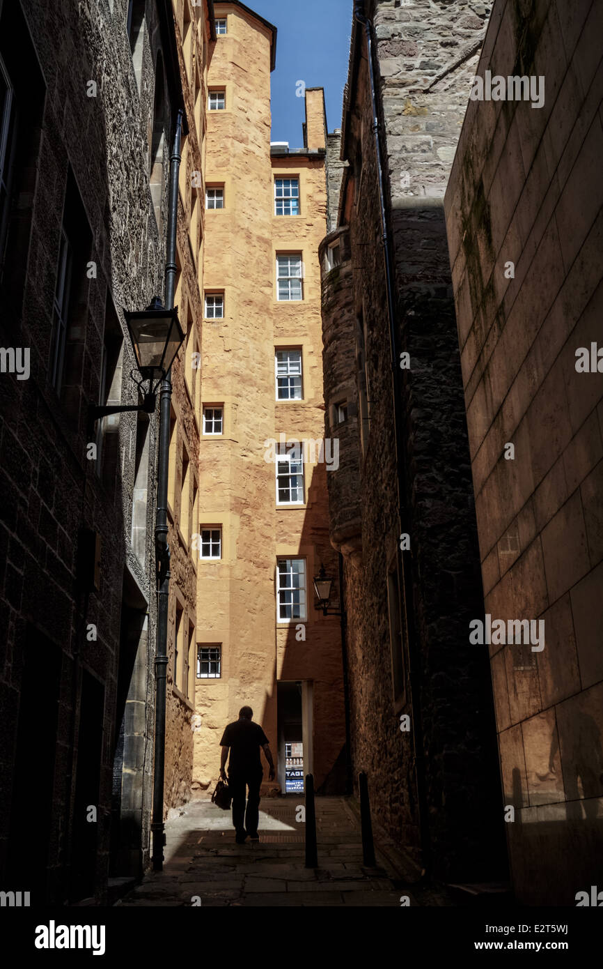 Man walking toward a bright orange building in an alley leading to the ...