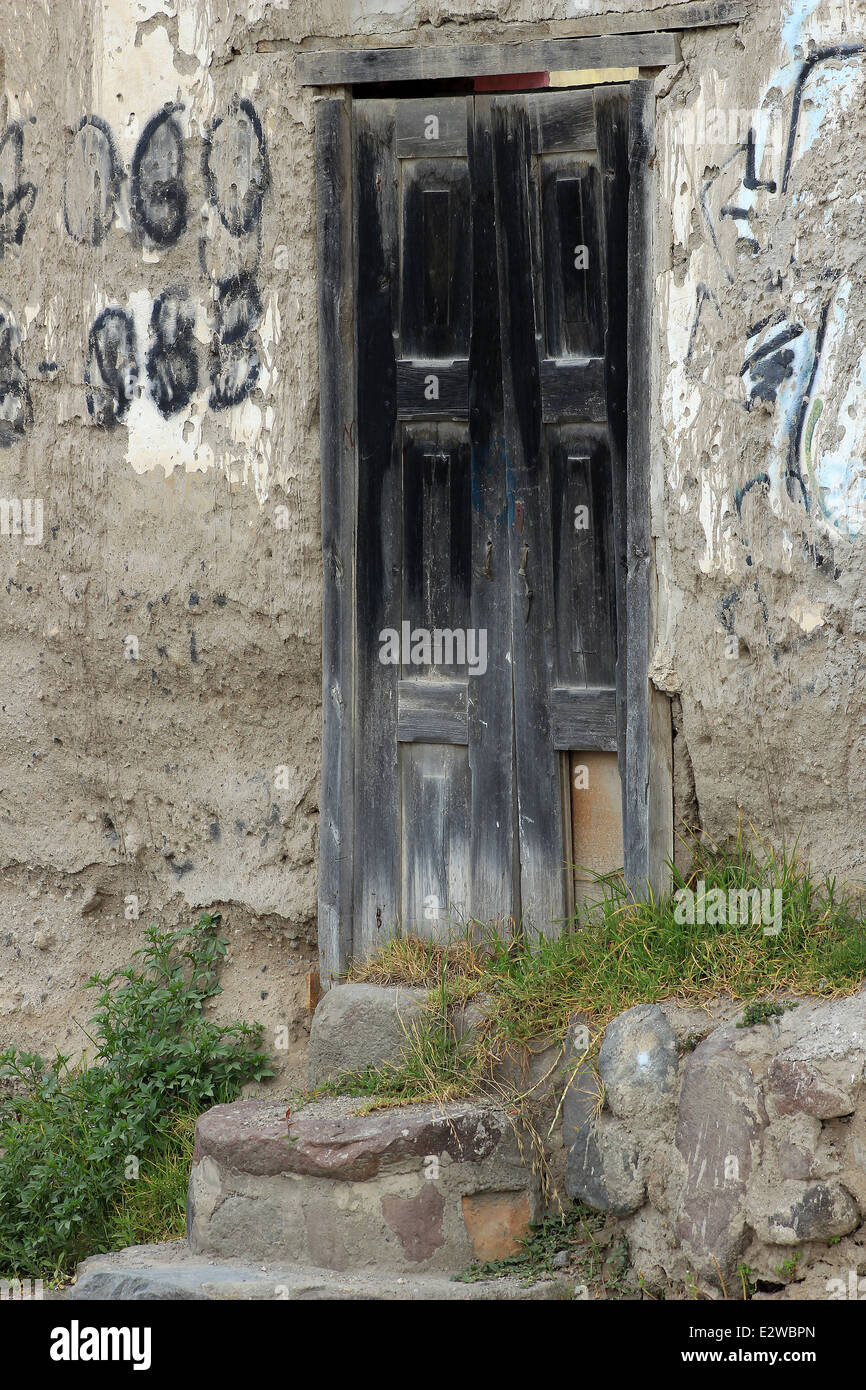 A weathered wooden door leading into the wall of a building in ...