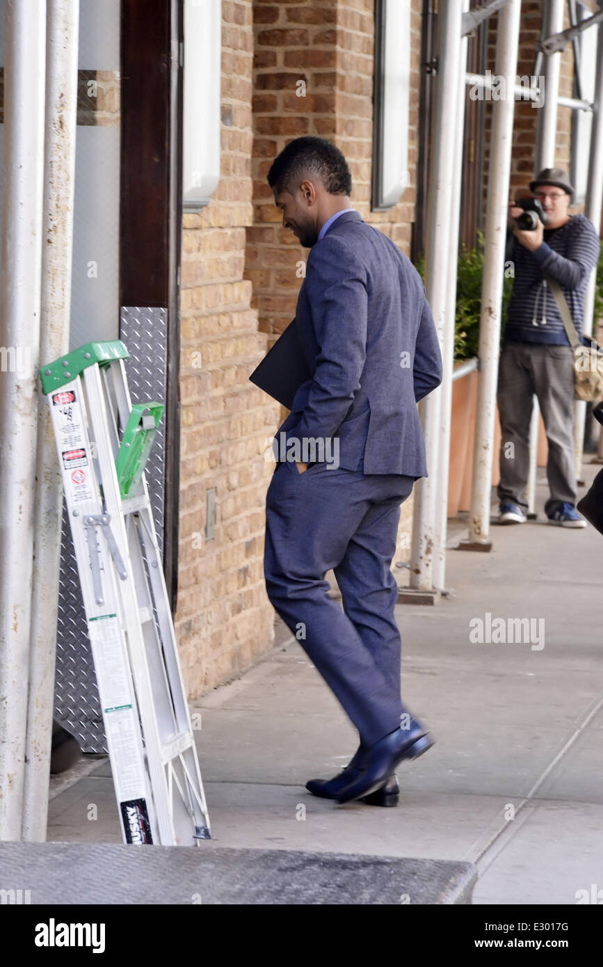 Usher arrives at a downtown hotel dressed in a smart suit and carrying ...