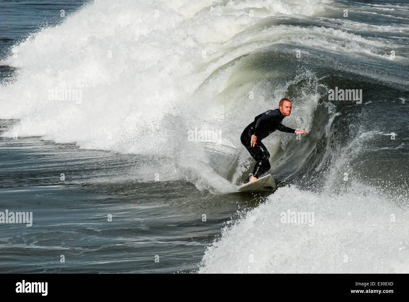Surfer outrunning a crashing tube and setting up to launch an aerial at ...
